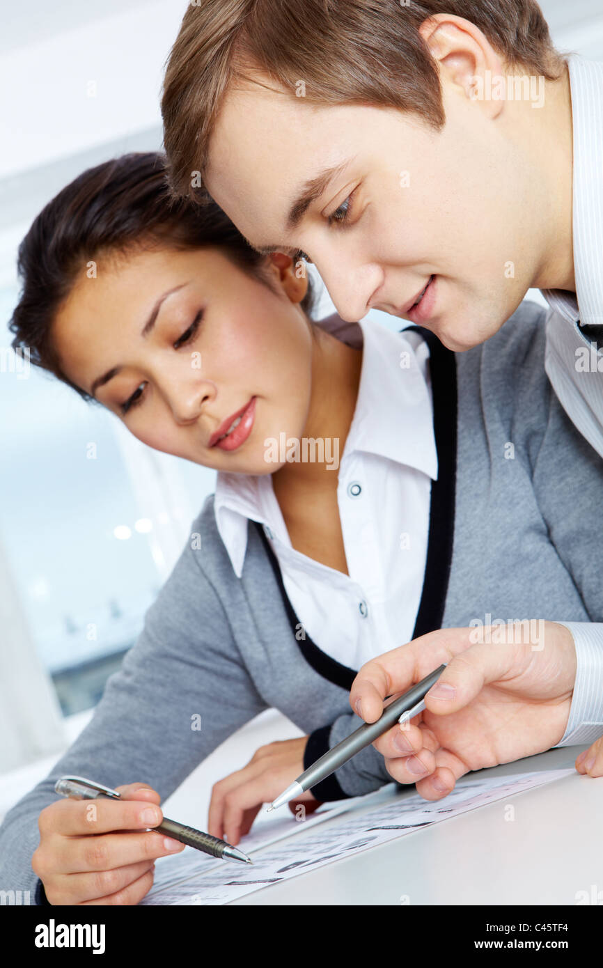 Successful businessman and his pretty colleague working with papers ...