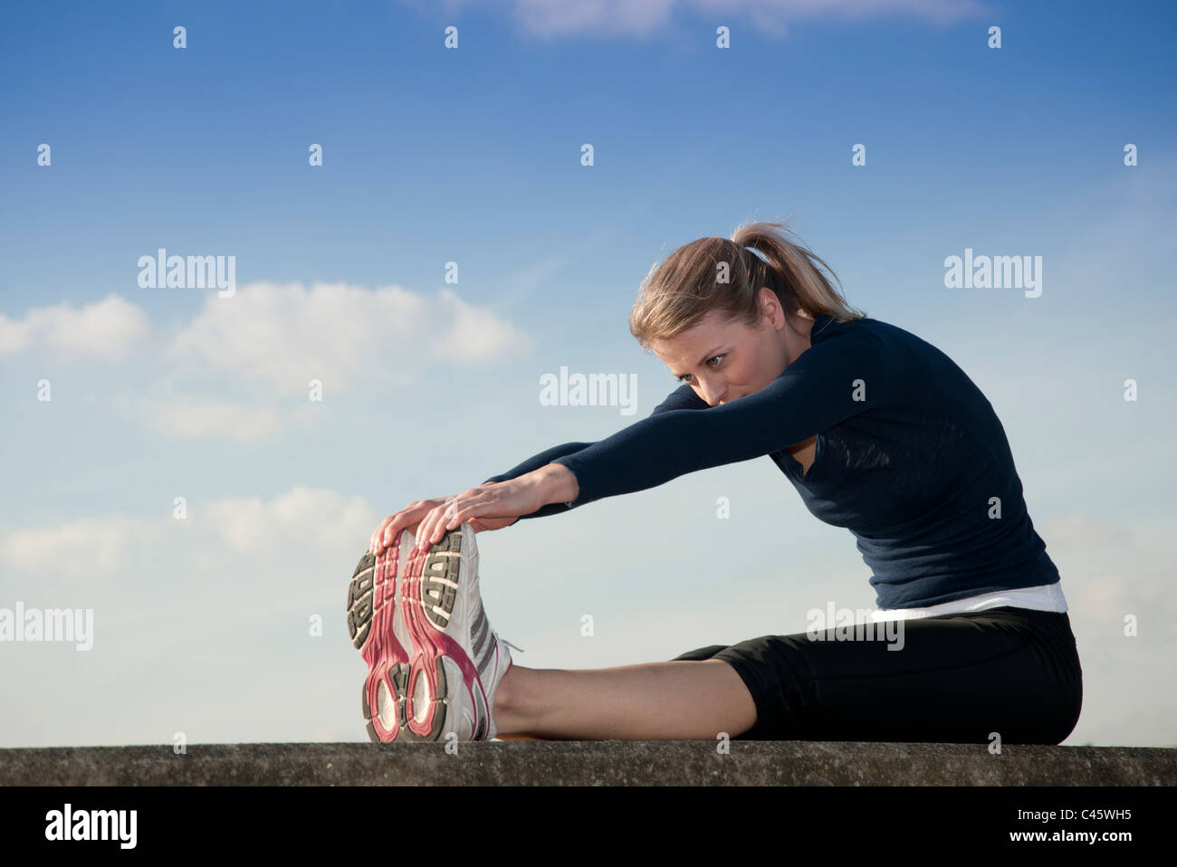 woman sitting stretching legs hamstrings touching toes training Stock ...