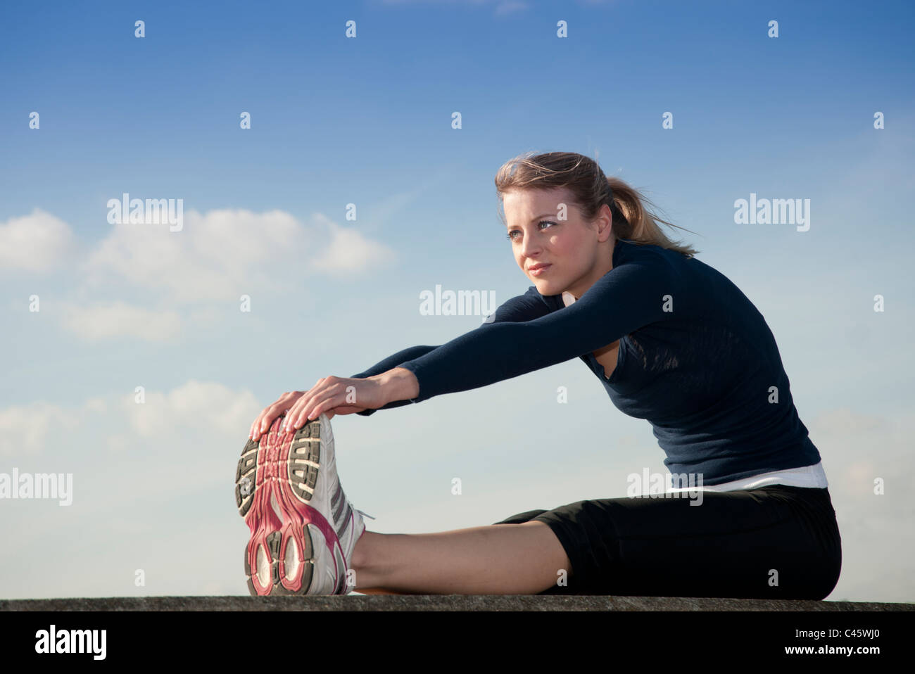woman sitting stretching legs hamstrings touching toes training Stock ...