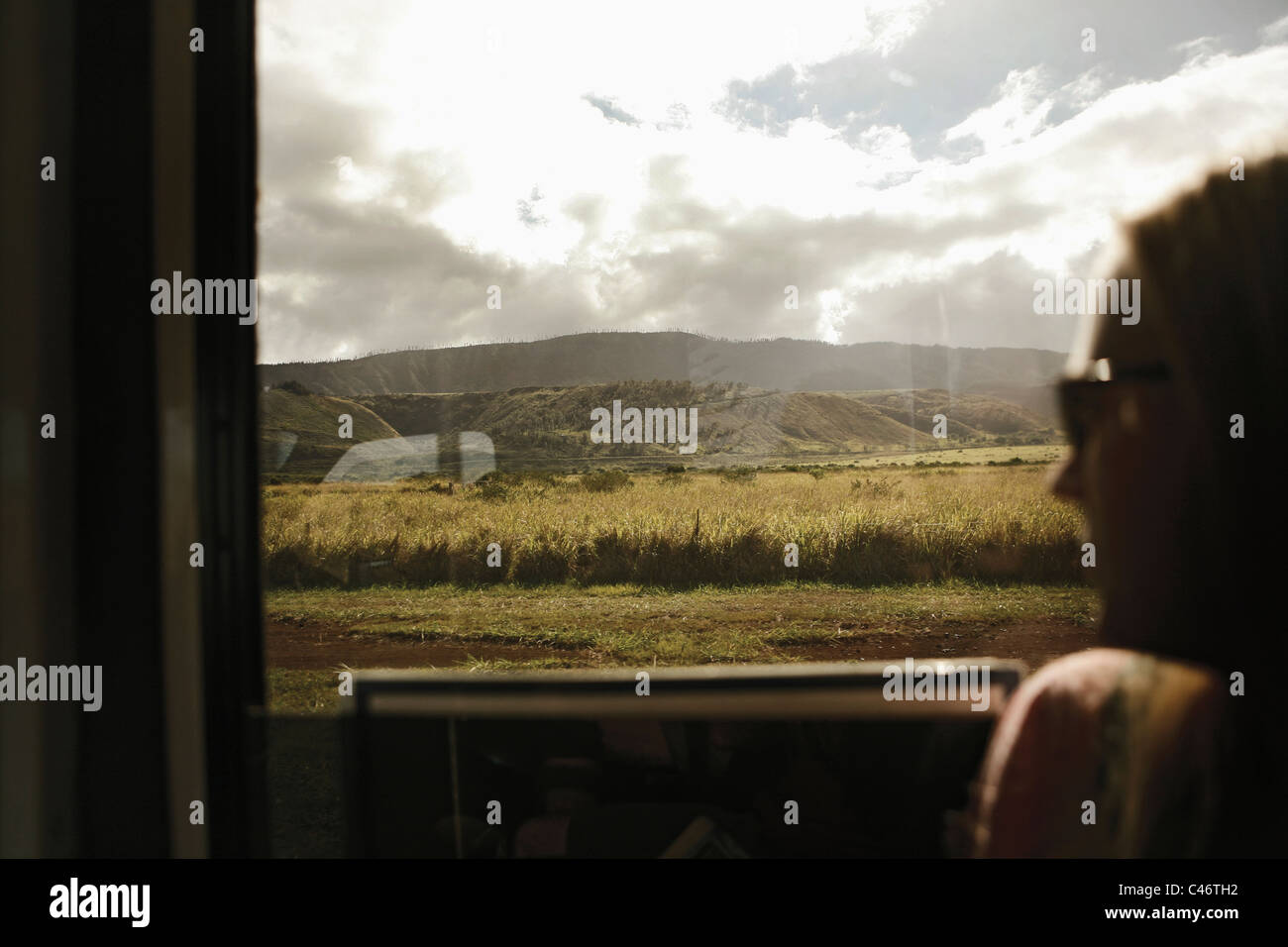 A woman looks out a train window at the Hawaiian countryside Stock ...