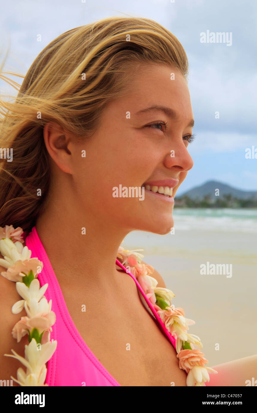 teenage girl in pink bikini wearing a flower lei with her surfboard on ...