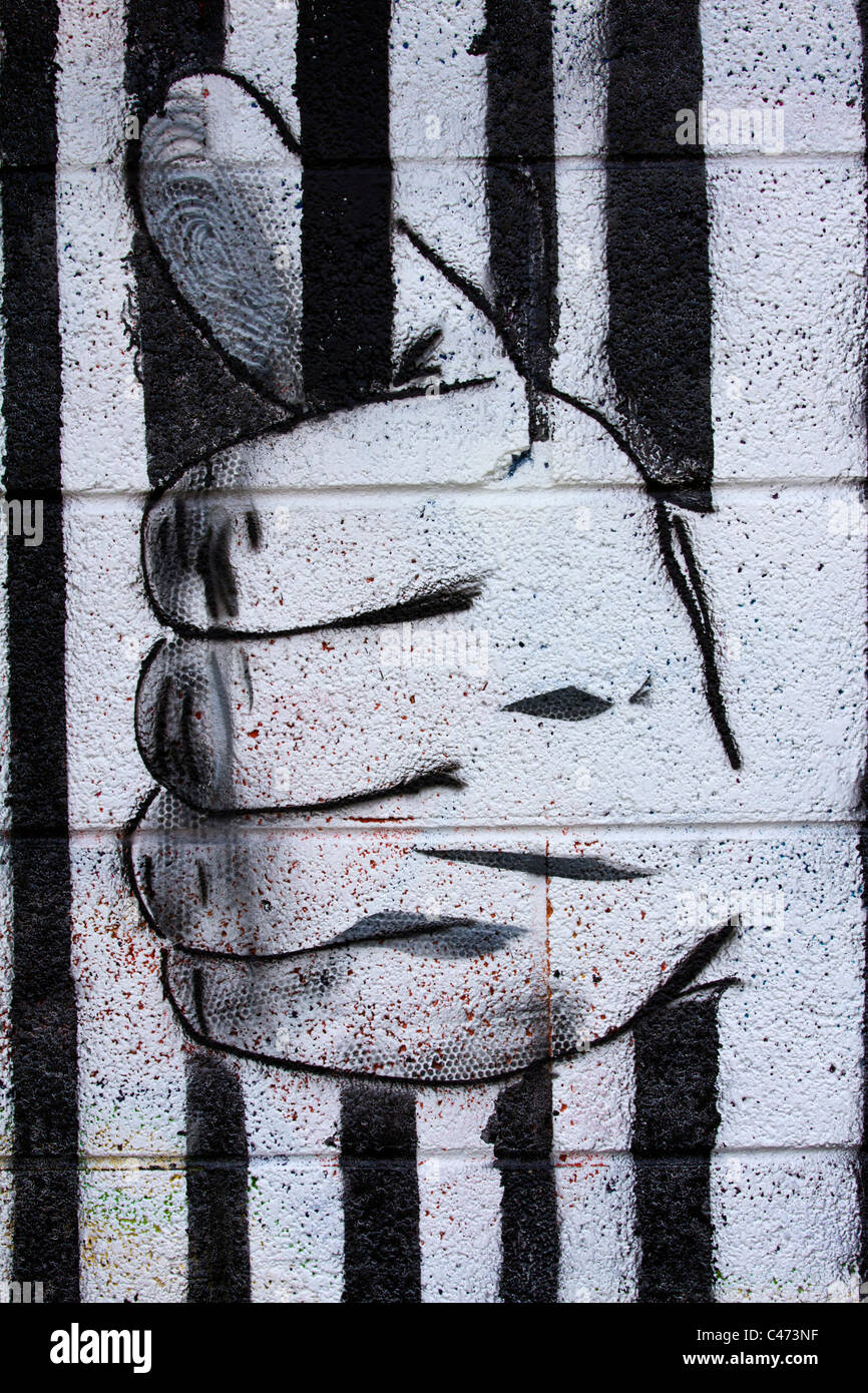 A graffiti mural of a hand clenching jail bars with detail including ...