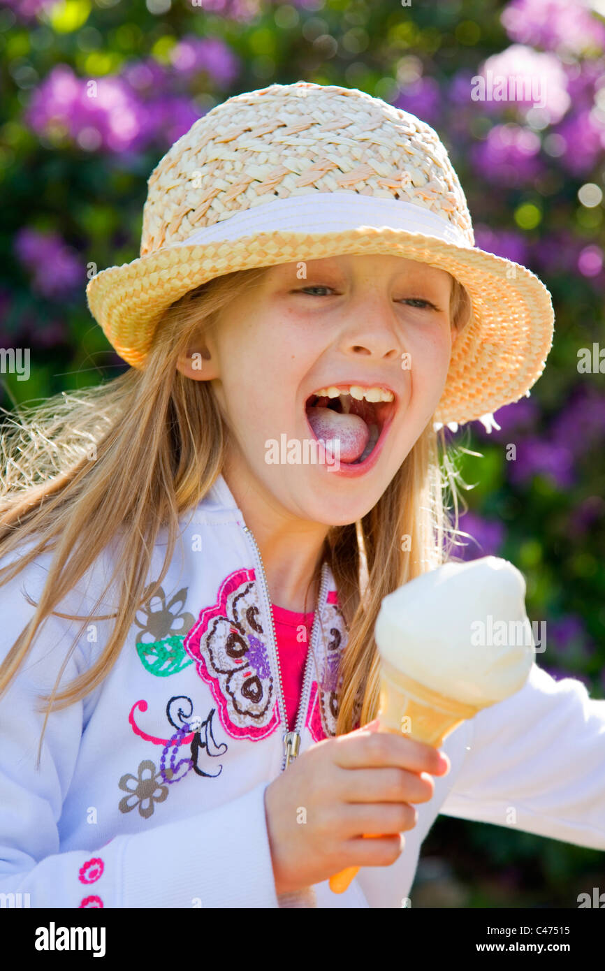Happy young girl laughing and playing in summer sunshine while eating ...