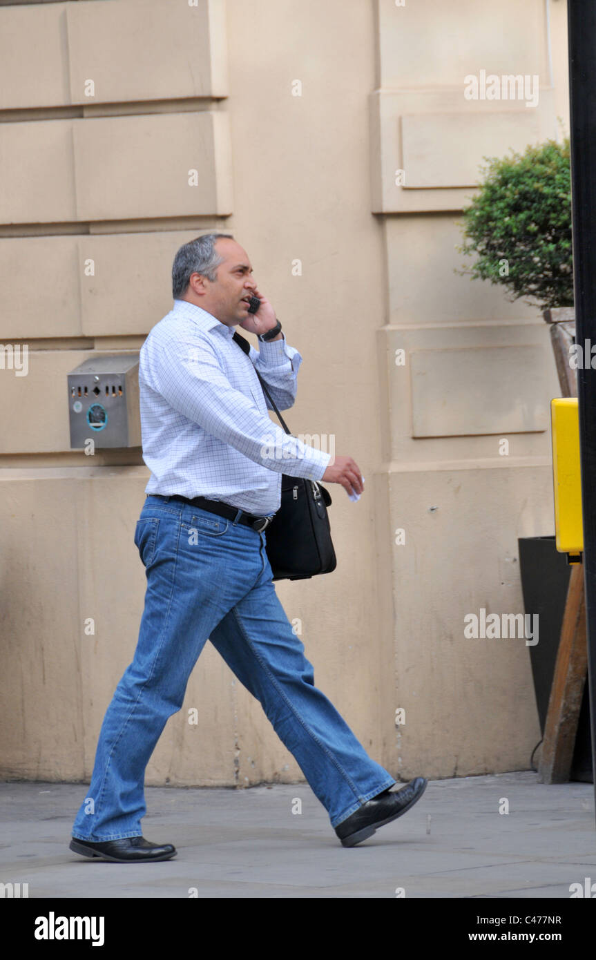 Man walking mobile phone talking street laptop bag Stock Photo - Alamy