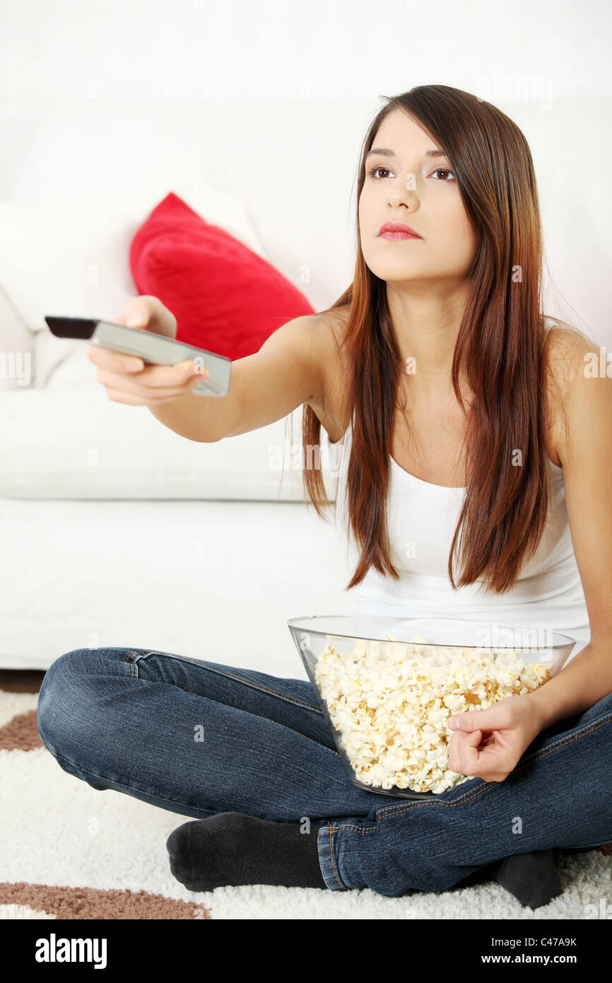 Girl watching TV having fun eating popcorn Stock Photo - Alamy