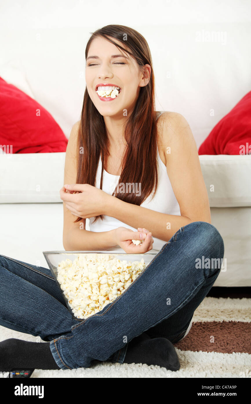 Girl watching TV having fun eating popcorn Stock Photo - Alamy