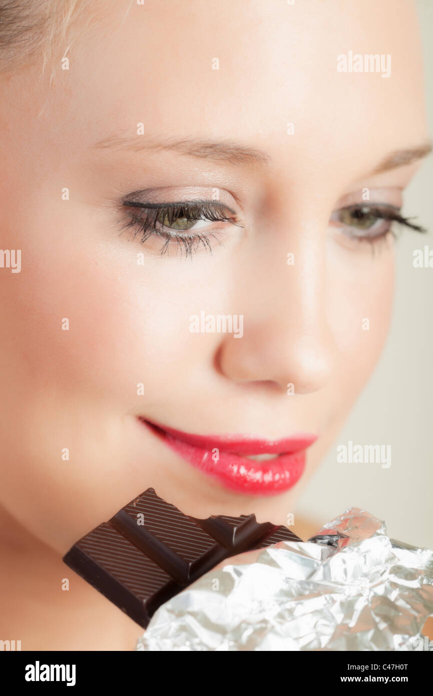 Closeup portrait of a pretty young woman biting chocolate Stock Photo ...