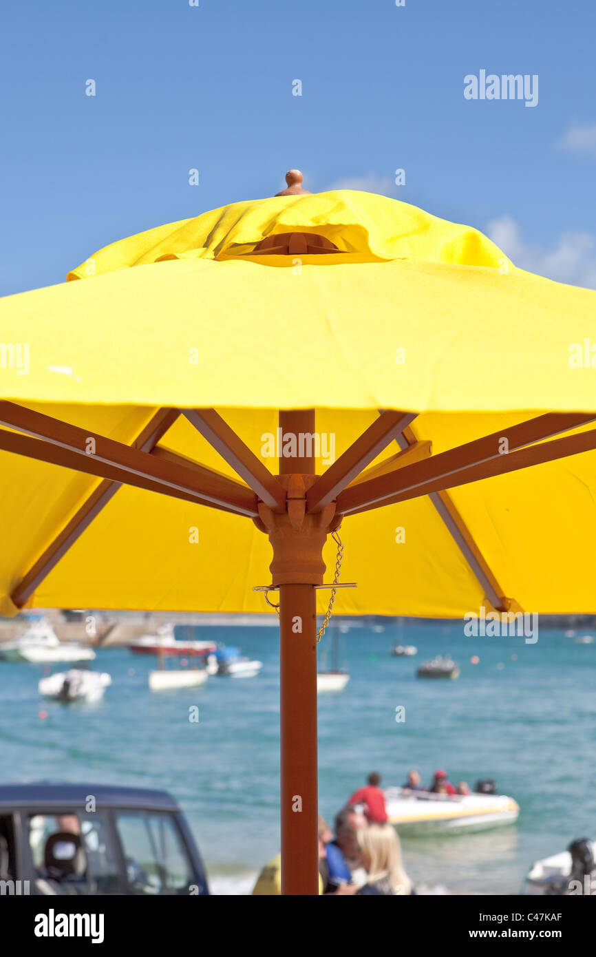Summer conceptual image of a bright yellow parasol at the seaside ...