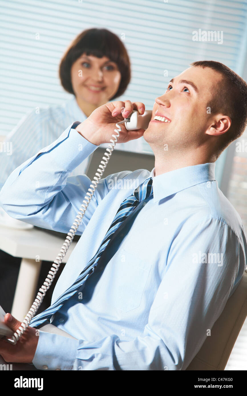 Portrait of happy businessman calling with secretary on background ...