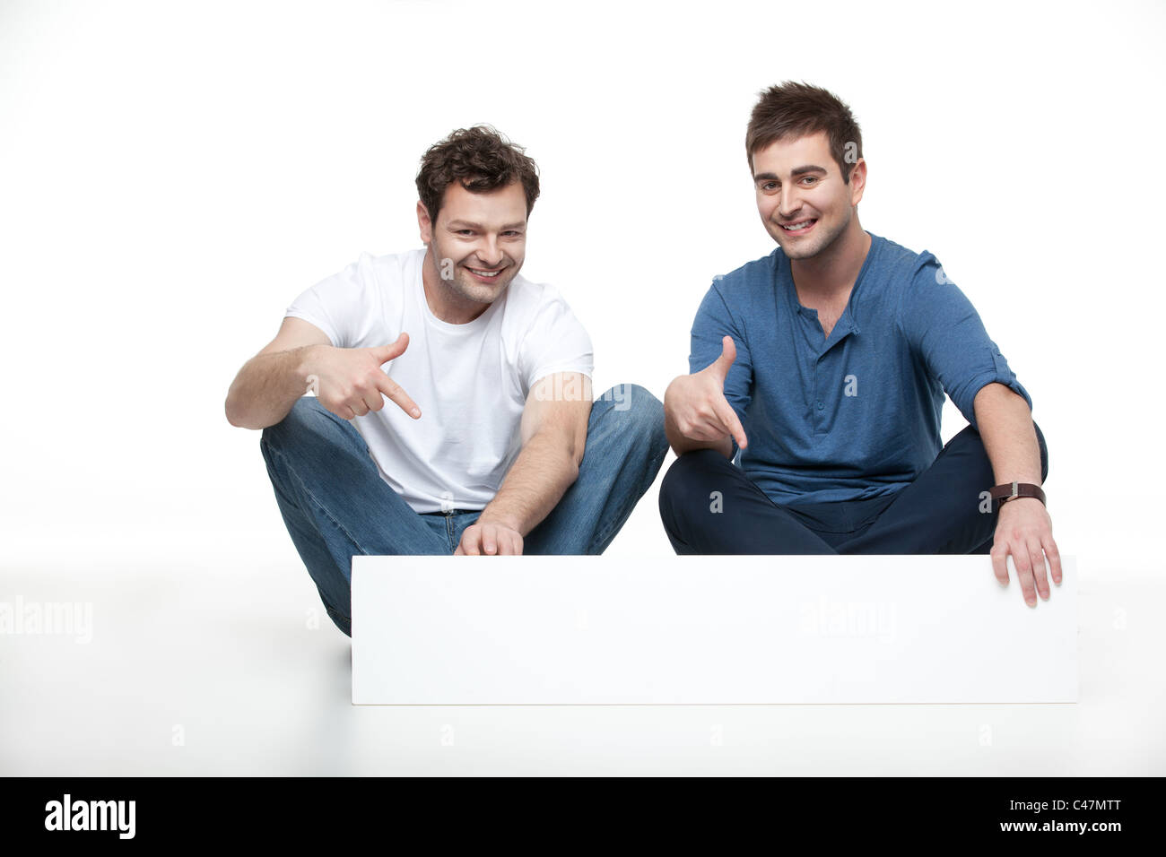 two young men sitting pointing blanck benner Stock Photo - Alamy