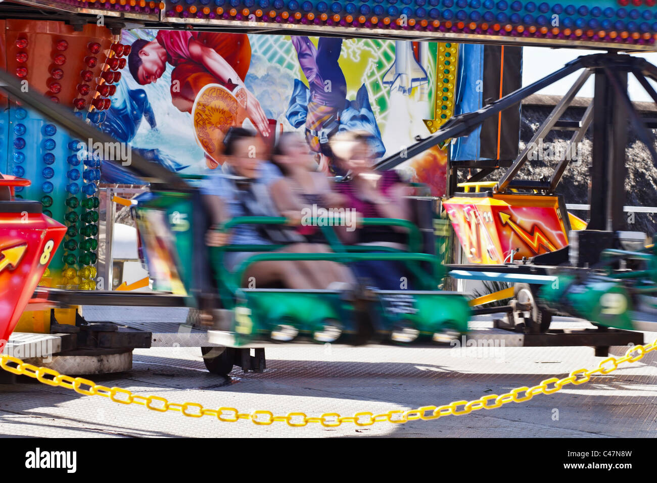 Three young girls spinning around at high speed on a funfair ride at an ...