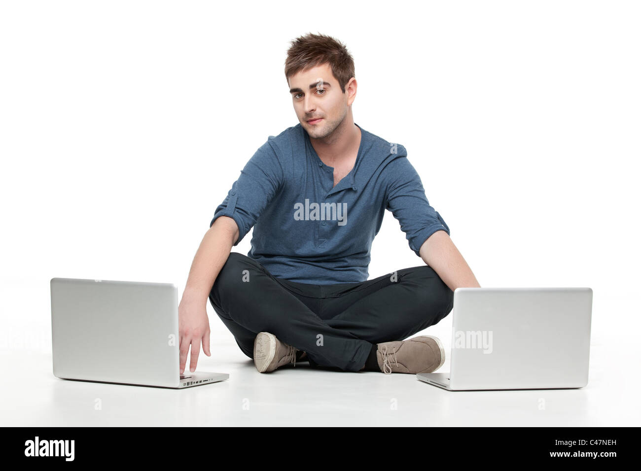 handsome man sitting behind two laptops Stock Photo - Alamy