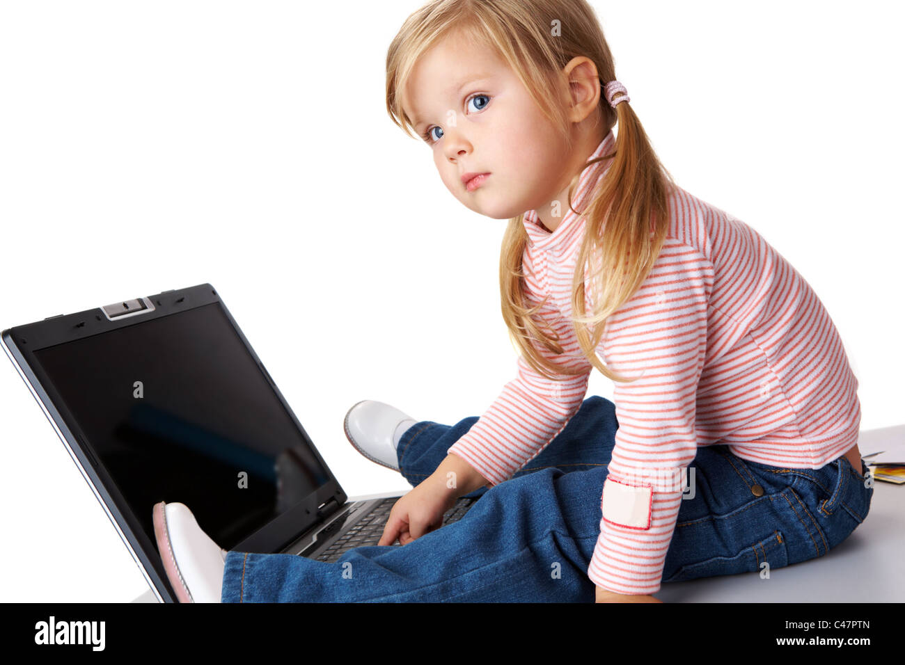 Curious girl sitting in front of laptop and looking aside Stock Photo ...