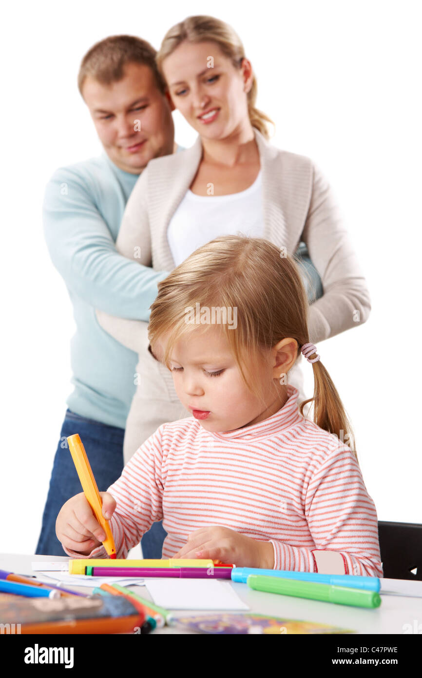 Photo of adorable girl drawing with highlighters with her parents ...