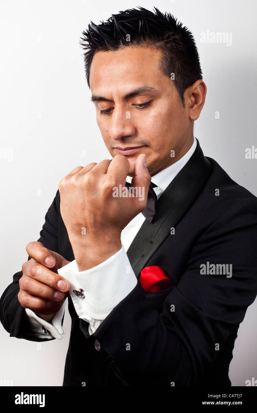 Half length portrait of a young Latin man buttoning cuff, London ...