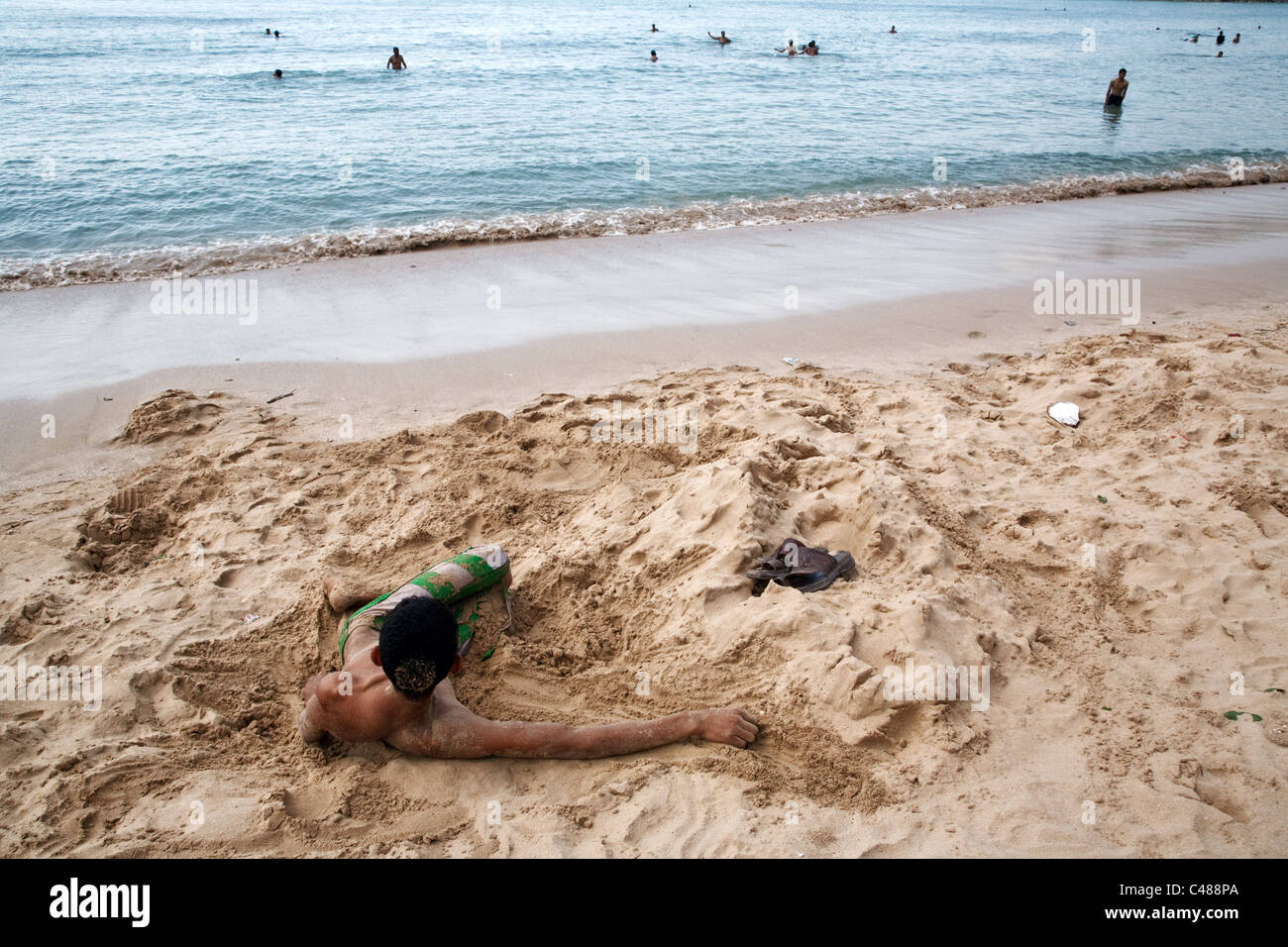 A young Yemeni man lying in the sand on the beach on the coast of Red ...