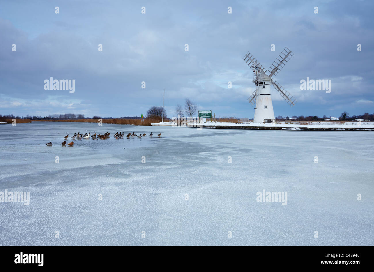 A partially frozen River Thurne with Thurne Windmill in the background ...