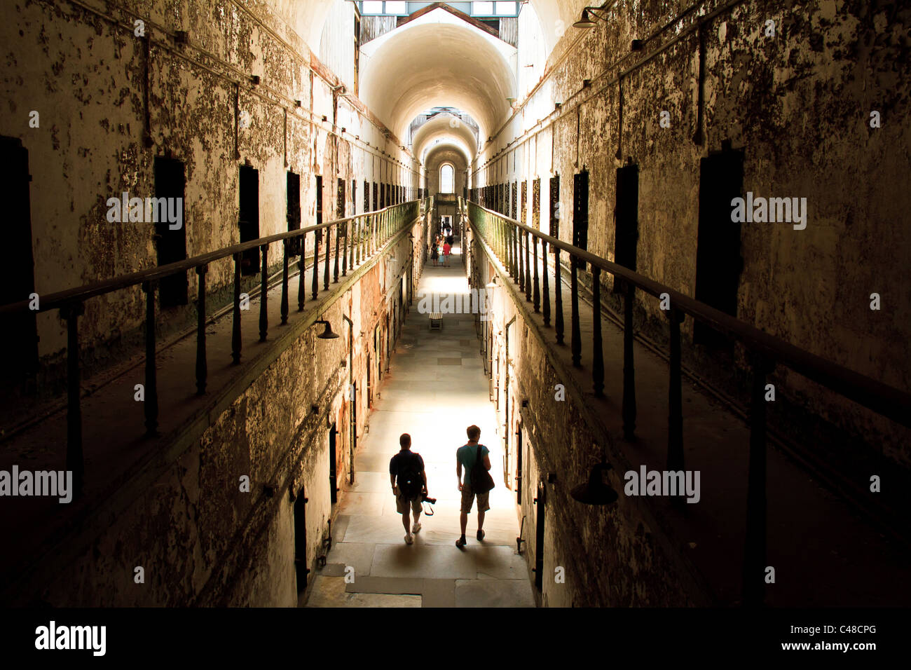 Tourists walk down a crumbling cellblock at Eastern State Penitentiary ...