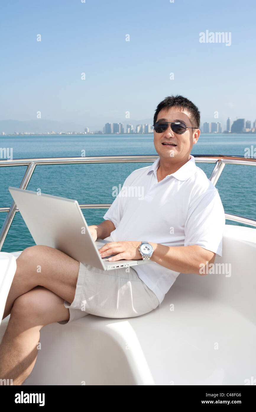 Man Using Laptop on Yacht Stock Photo - Alamy