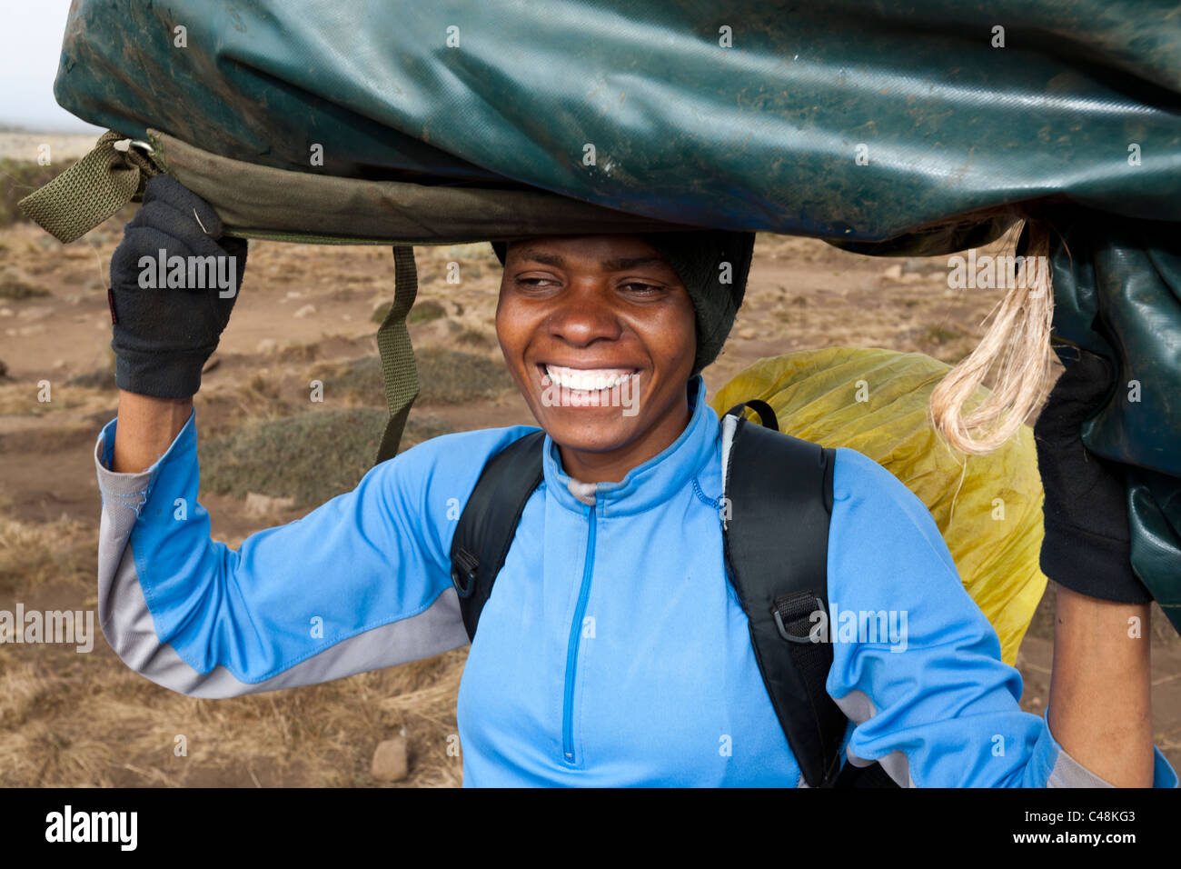 A female porter smiles at camp, Kilimanjaro National Park, Tanzania ...