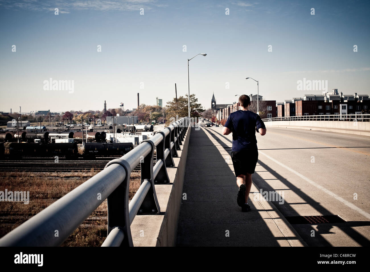 A man running on a bridge heading towards Baltimore City Stock Photo ...