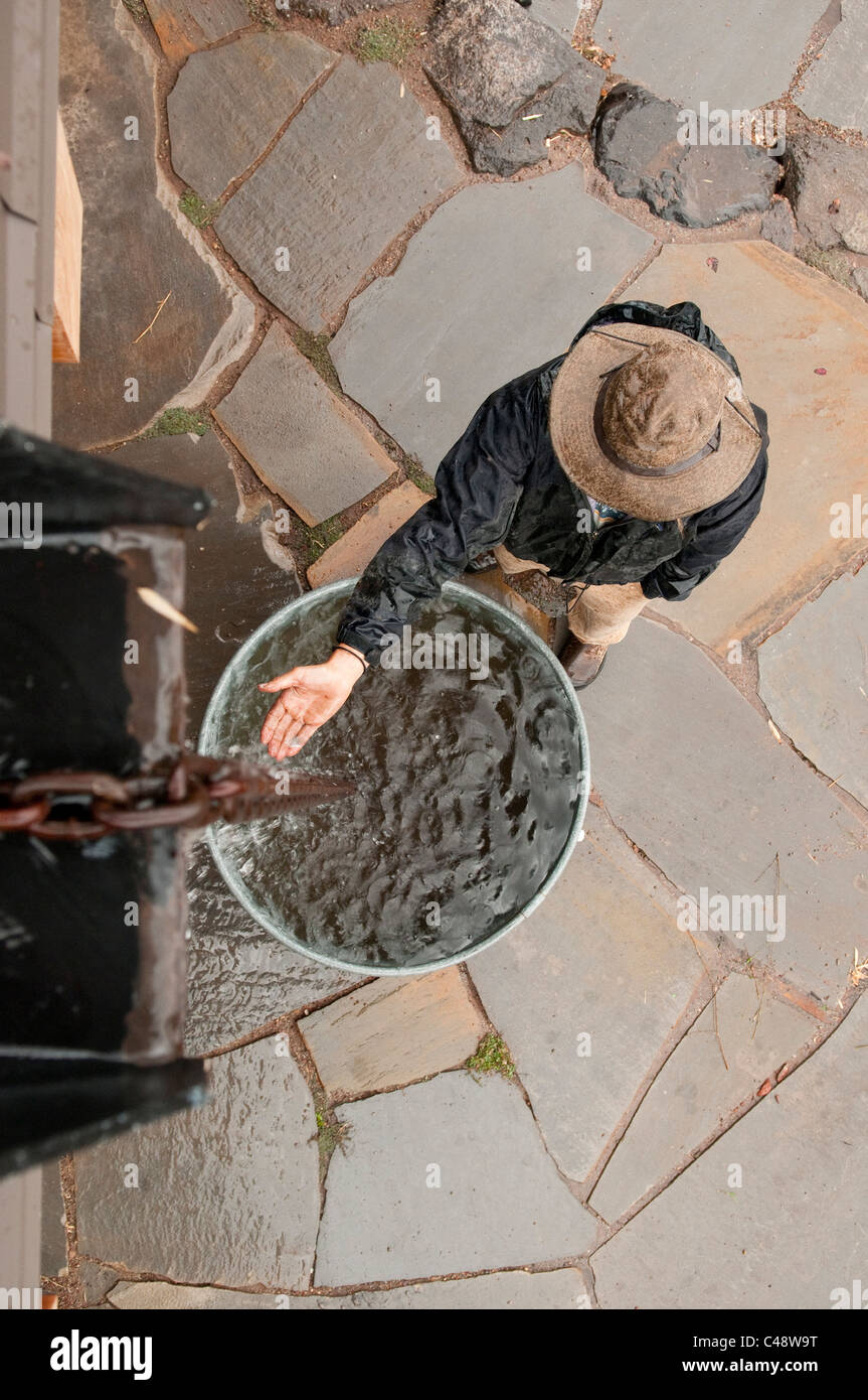 View from above of a woman standing by a rain catchment barrel, holding ...
