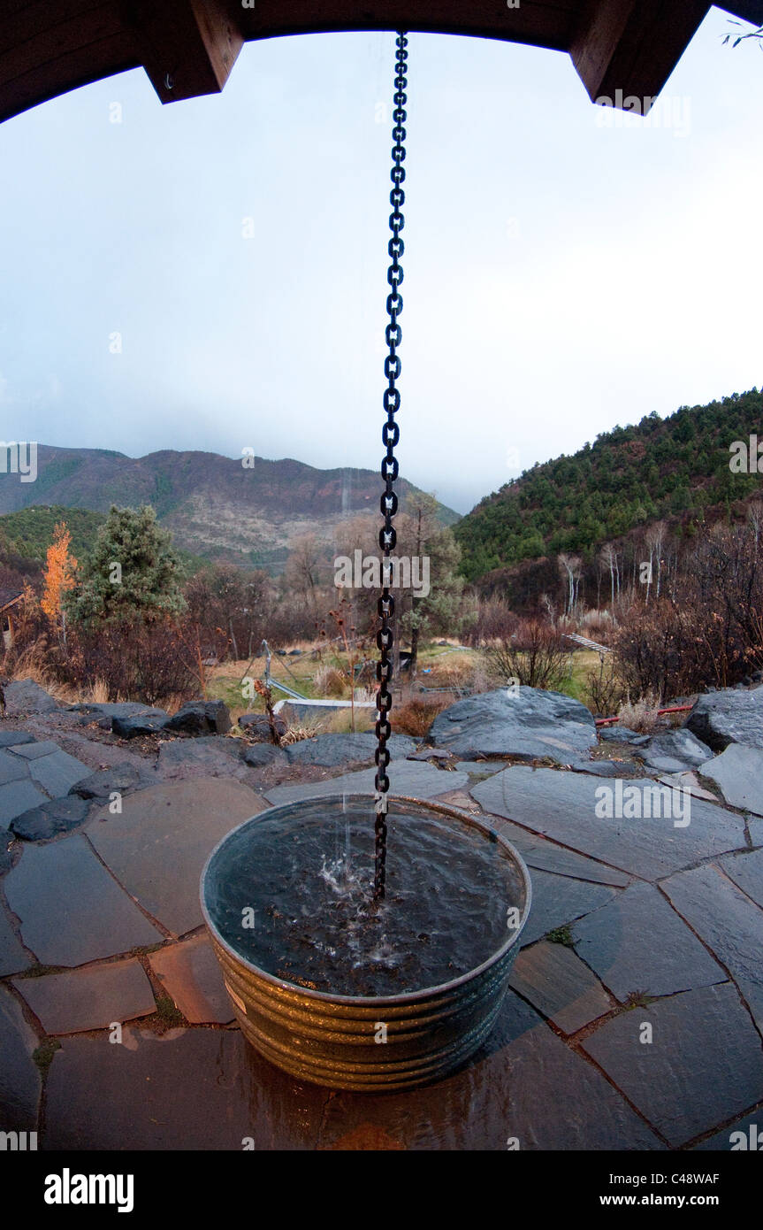 Rainwater collects from a chain into a barrel on a Colorado patio with ...