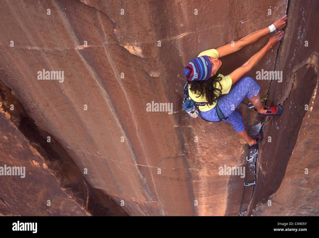 A woman rock climbs on the sandstone walls of Indian Creek, Canyonlands ...
