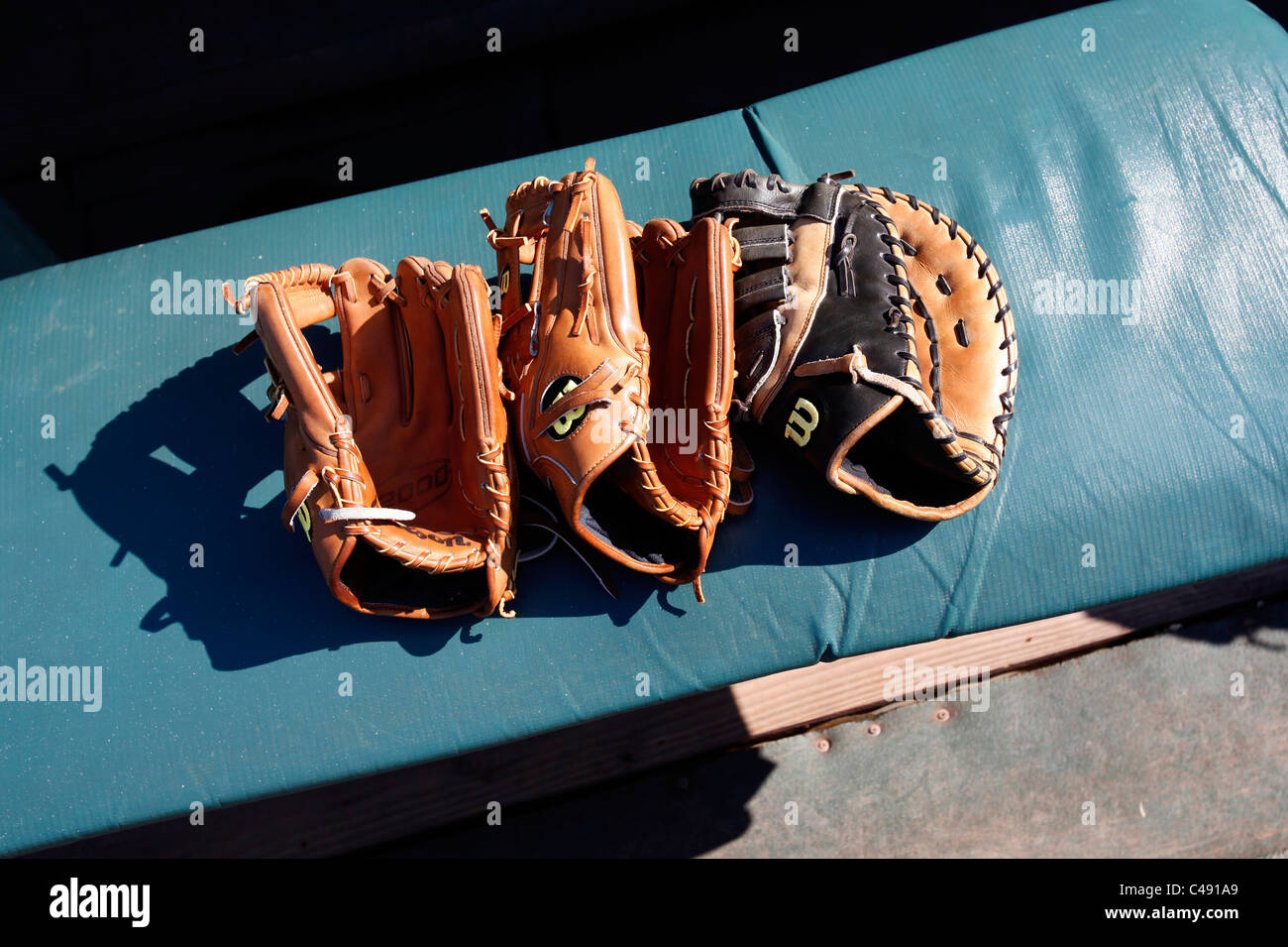 baseball gloves on a bench Stock Photo - Alamy