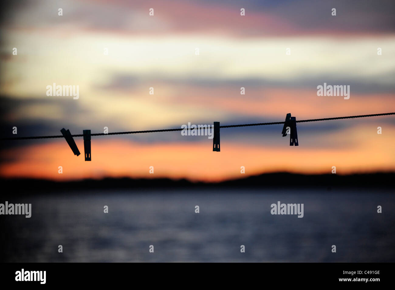 An empty washing line with pegs silhouetted against a sunsetting sky on ...