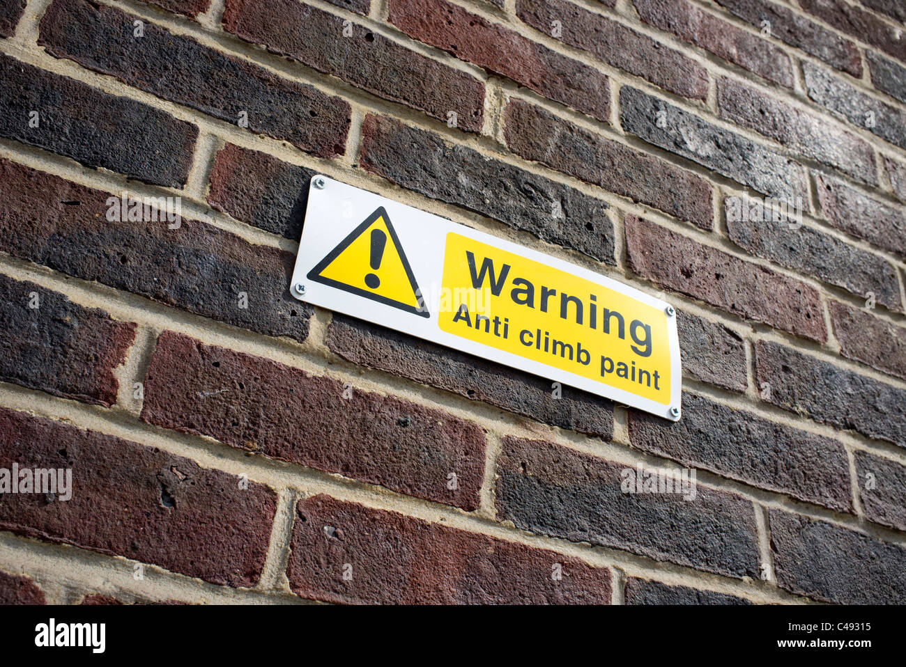 brick wall with a sign warning anti climb paint Stock Photo - Alamy