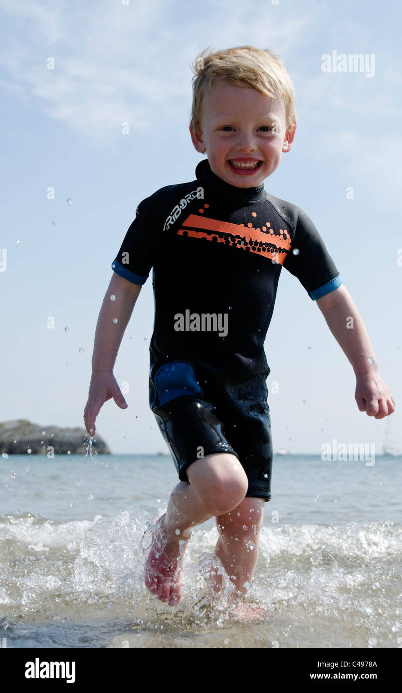 A young boy running through the sea, smiling and splashing Stock Photo ...