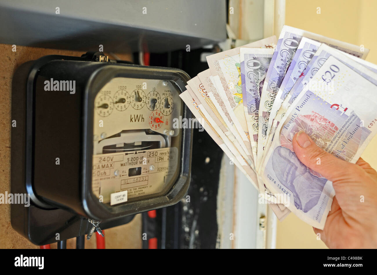 Woman holding cash in front of electric meter after learning of energy ...