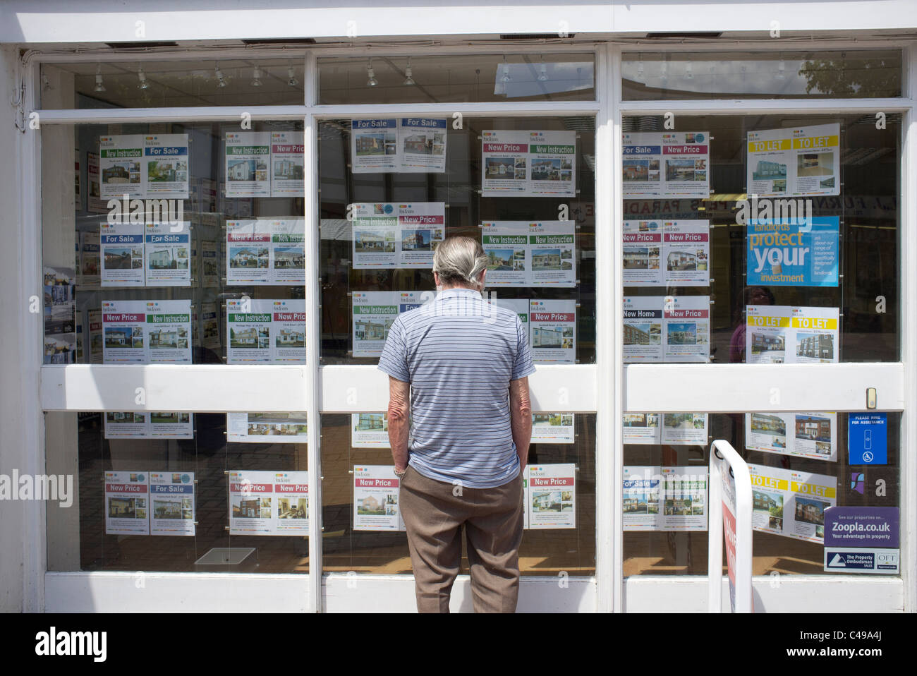 man looking in an estate agents window Stock Photo - Alamy