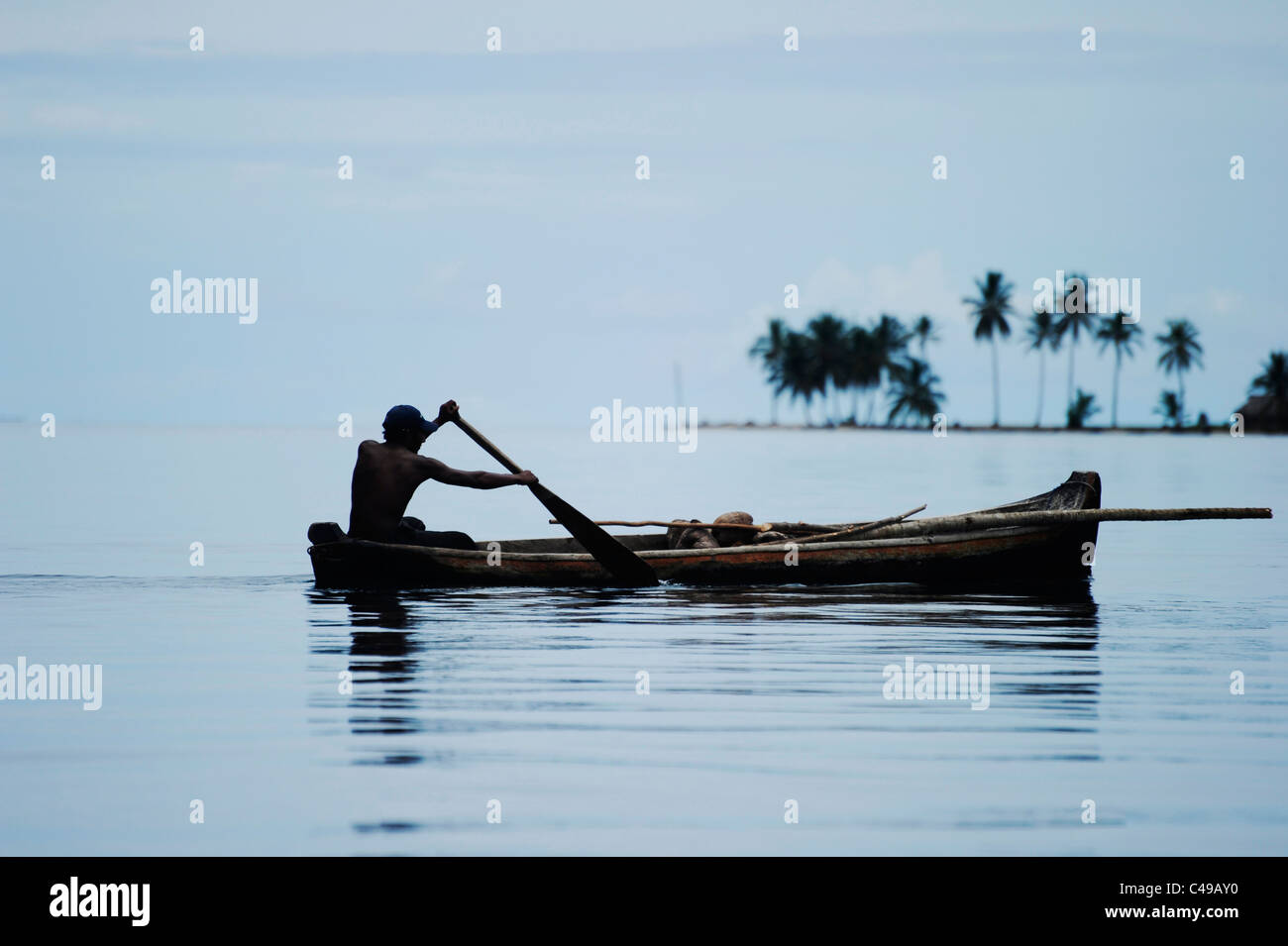 View of an indigenous Kuna man rowing his boat in front of an island in ...