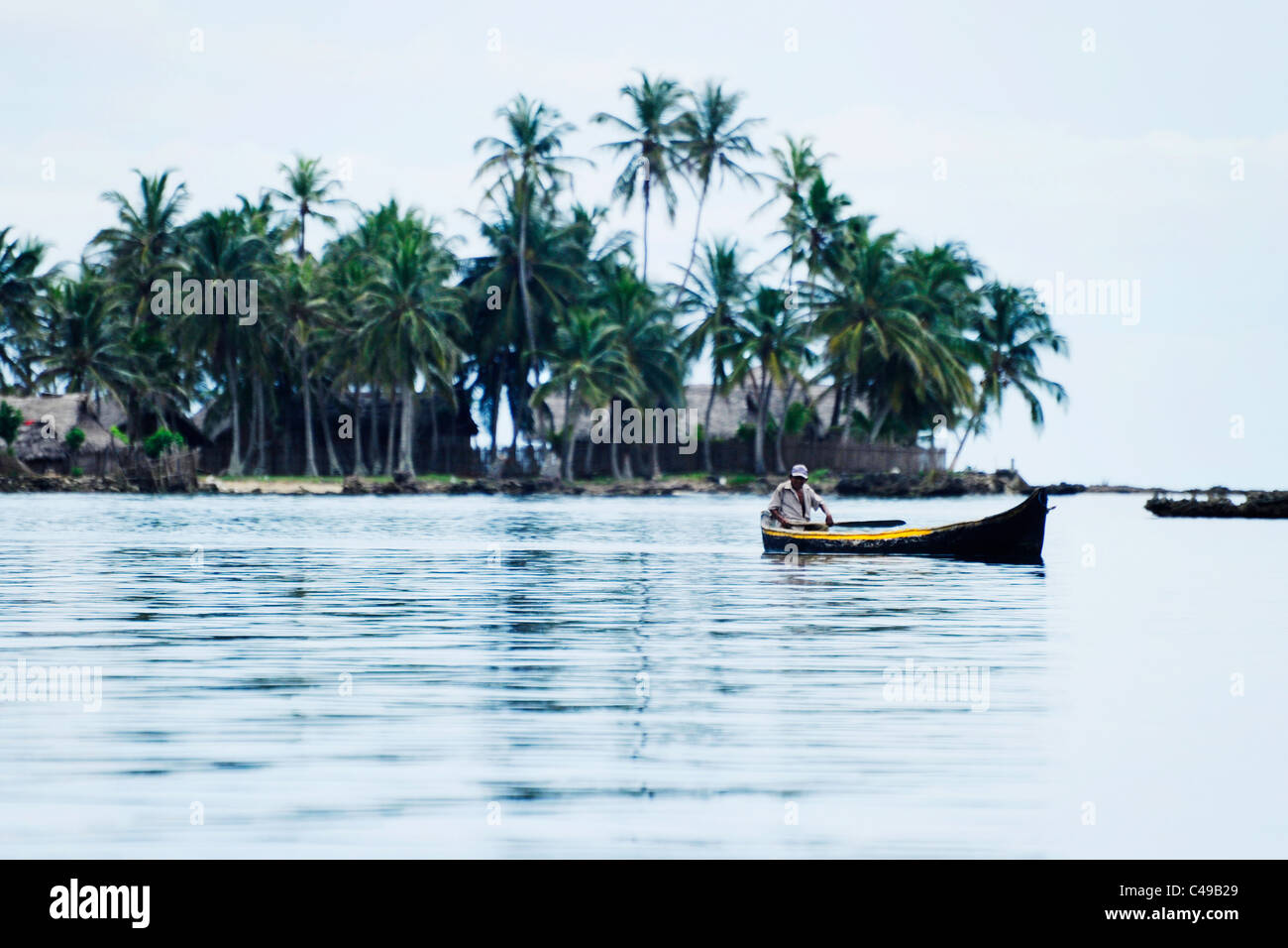 View of an indigenous Kuna man rowing his boat in front of an island in ...