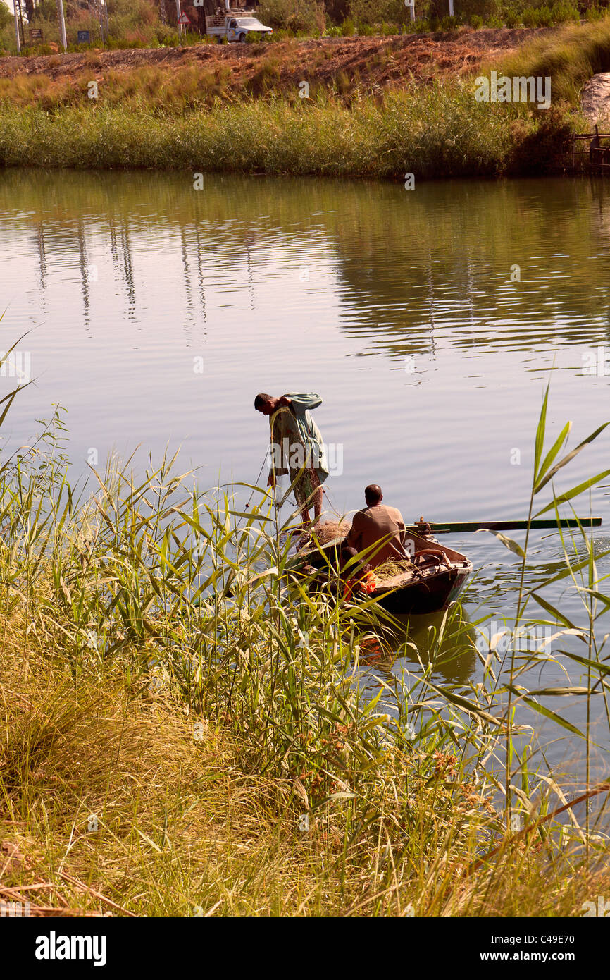 Two fishermen in a small boat check their nets Stock Photo - Alamy
