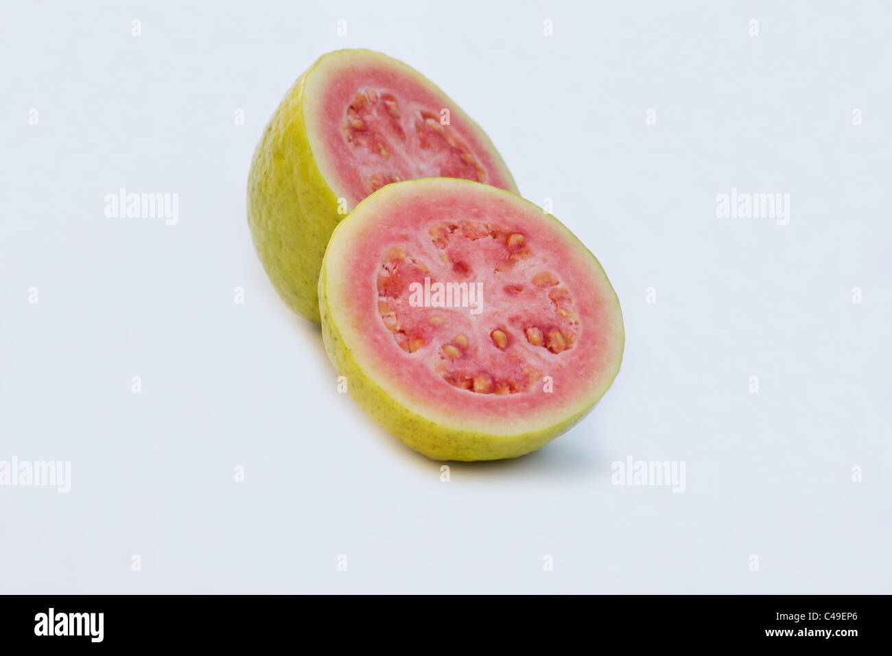Close-up of guava (Psidium guajava) cut in half on white background ...