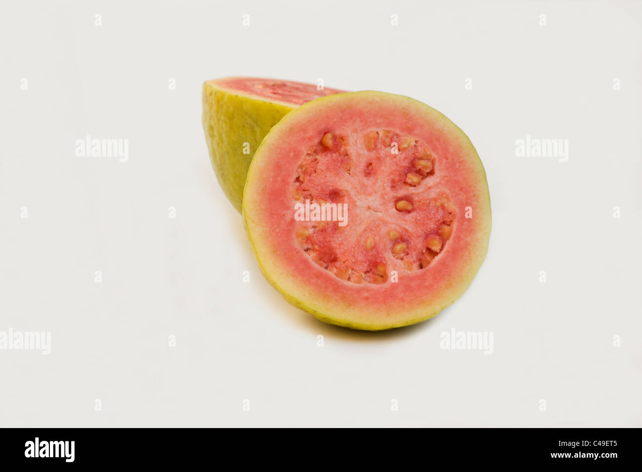 Close-up of guava (Psidium guajava) cut in half on white background ...