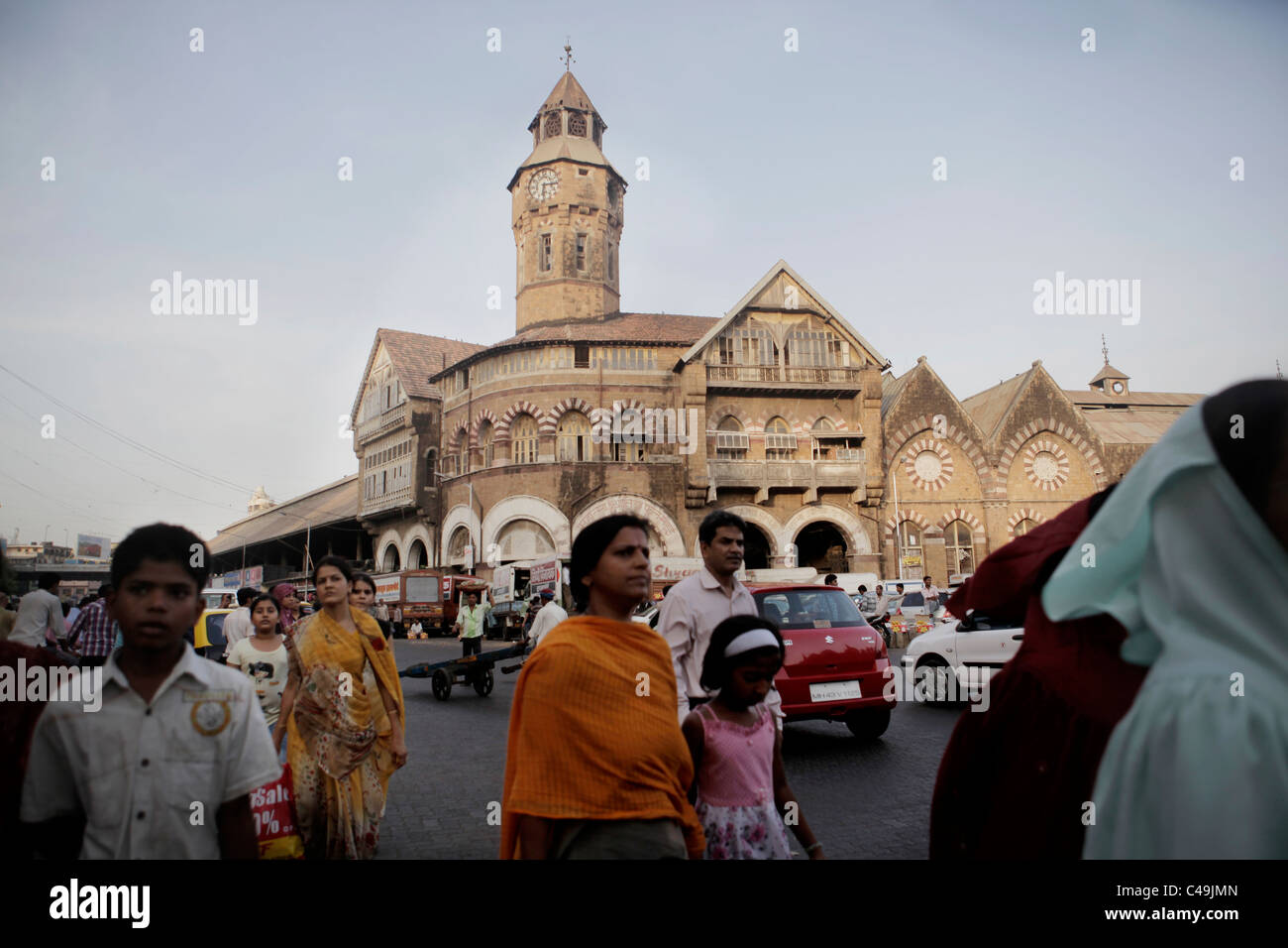 People walk along a crowded street in india with an ornate building in ...