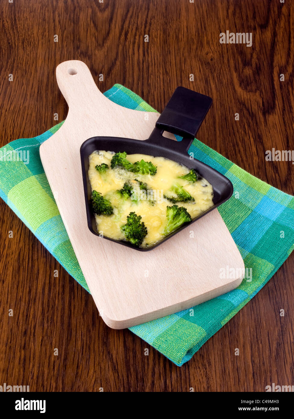 Raclette pan with cheese and broccoli on chopping board Stock Photo - Alamy