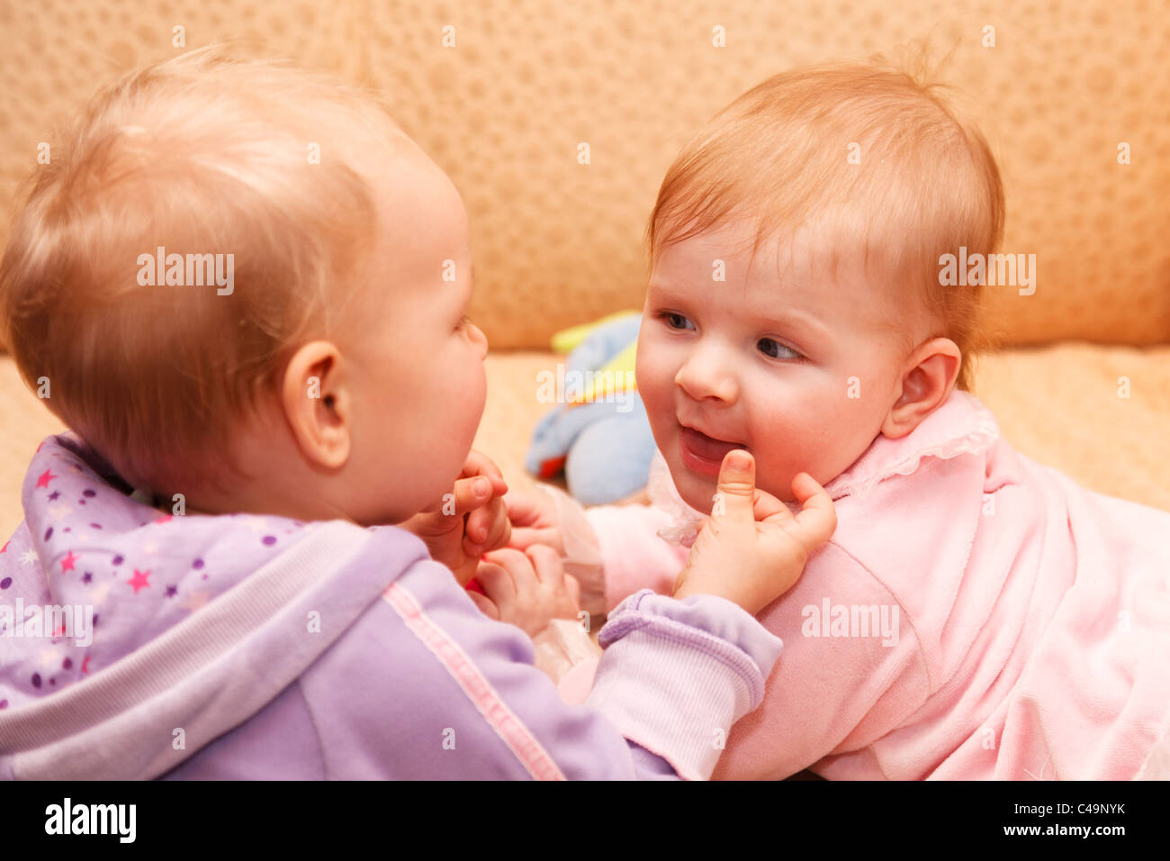 Two babies playing on sofa Stock Photo - Alamy