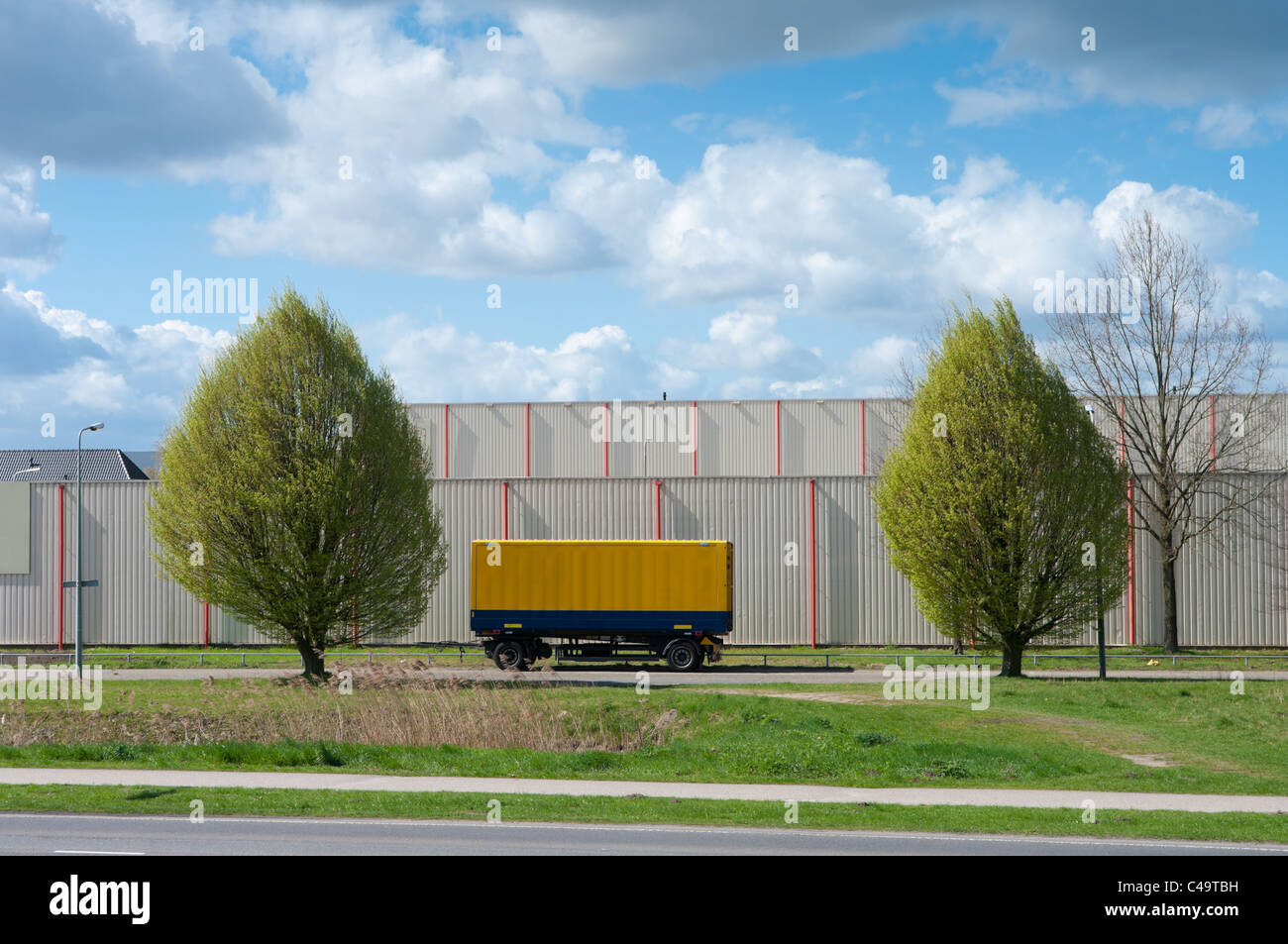 yellow trailer parked in front of a warehouse Stock Photo - Alamy