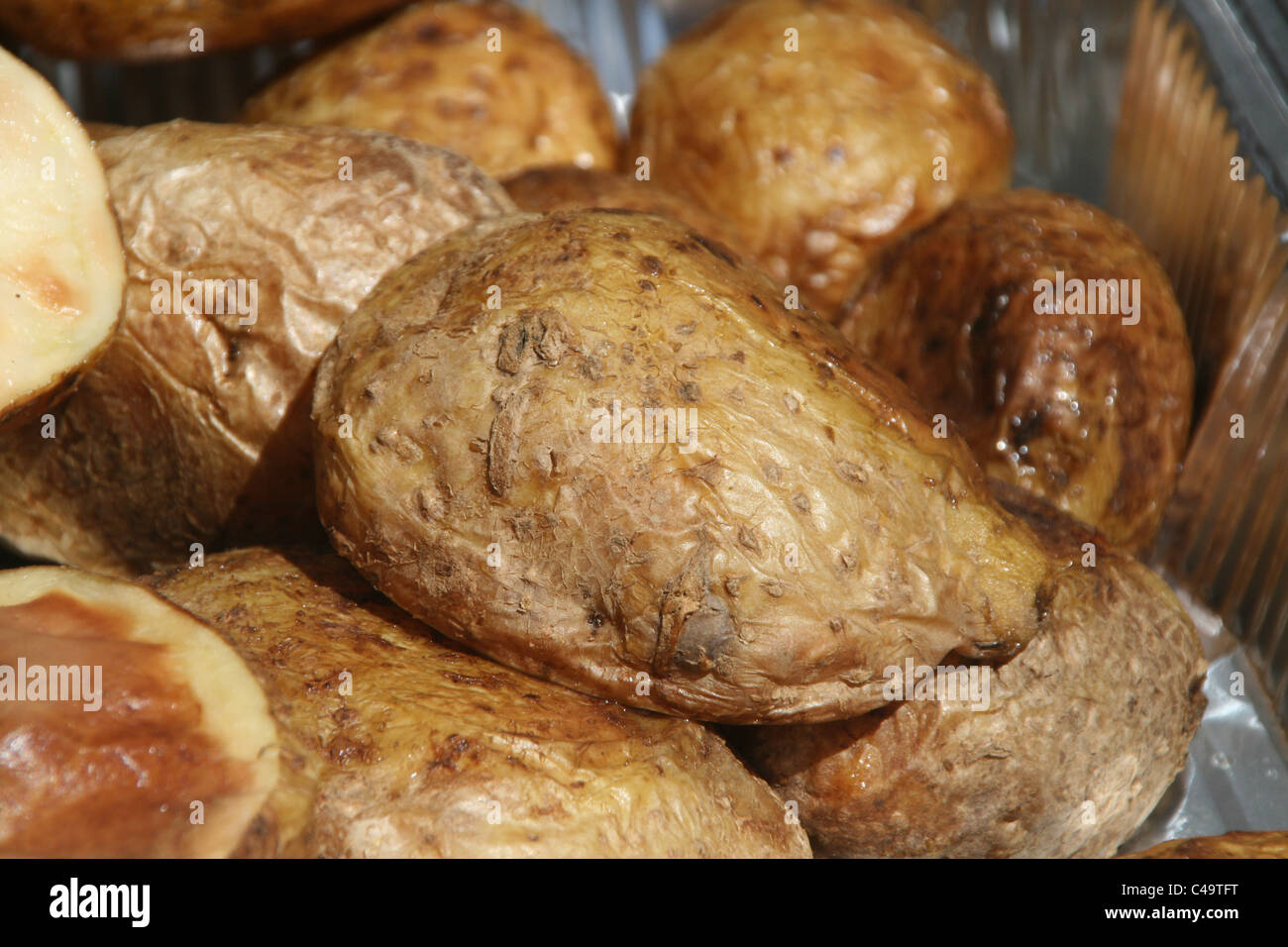 pile of cooked jacket potatoes on silver foil tray Stock Photo - Alamy