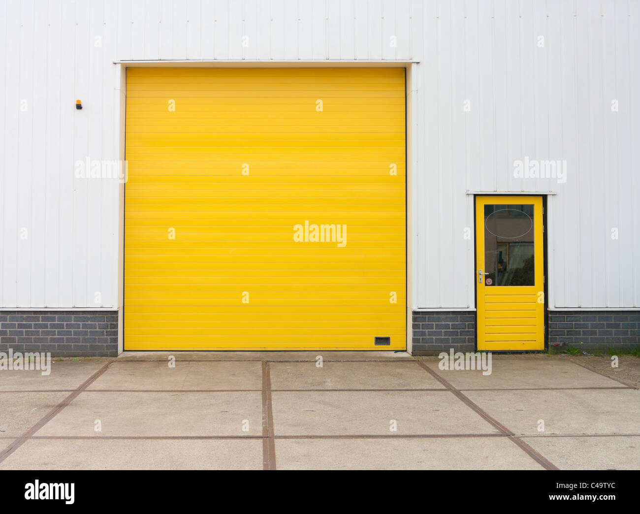 small industrial warehouse with a single yellow roller door Stock Photo ...