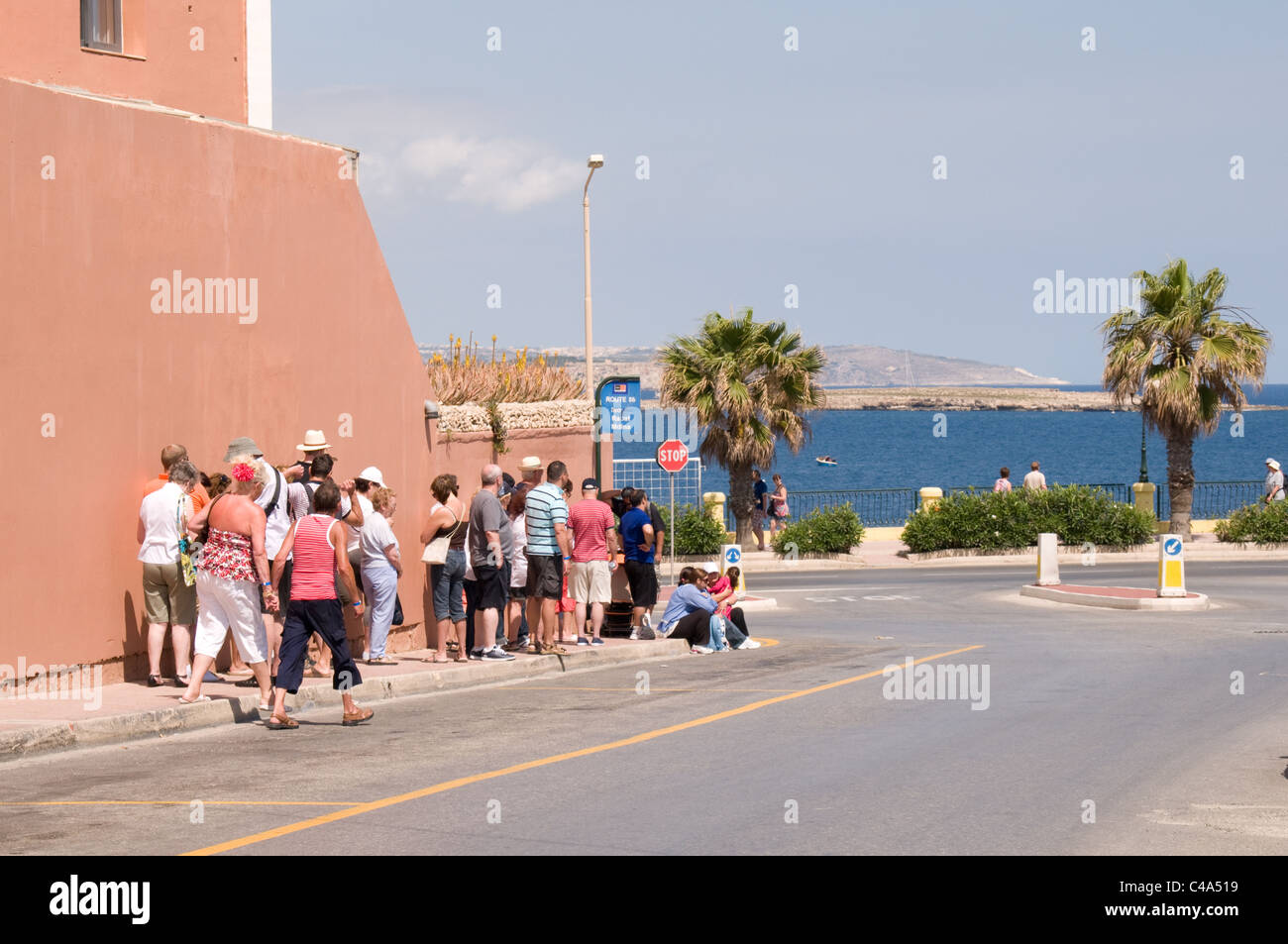 A queue of tourists wait at a bus stop in Bugibba, Malta for the next ...