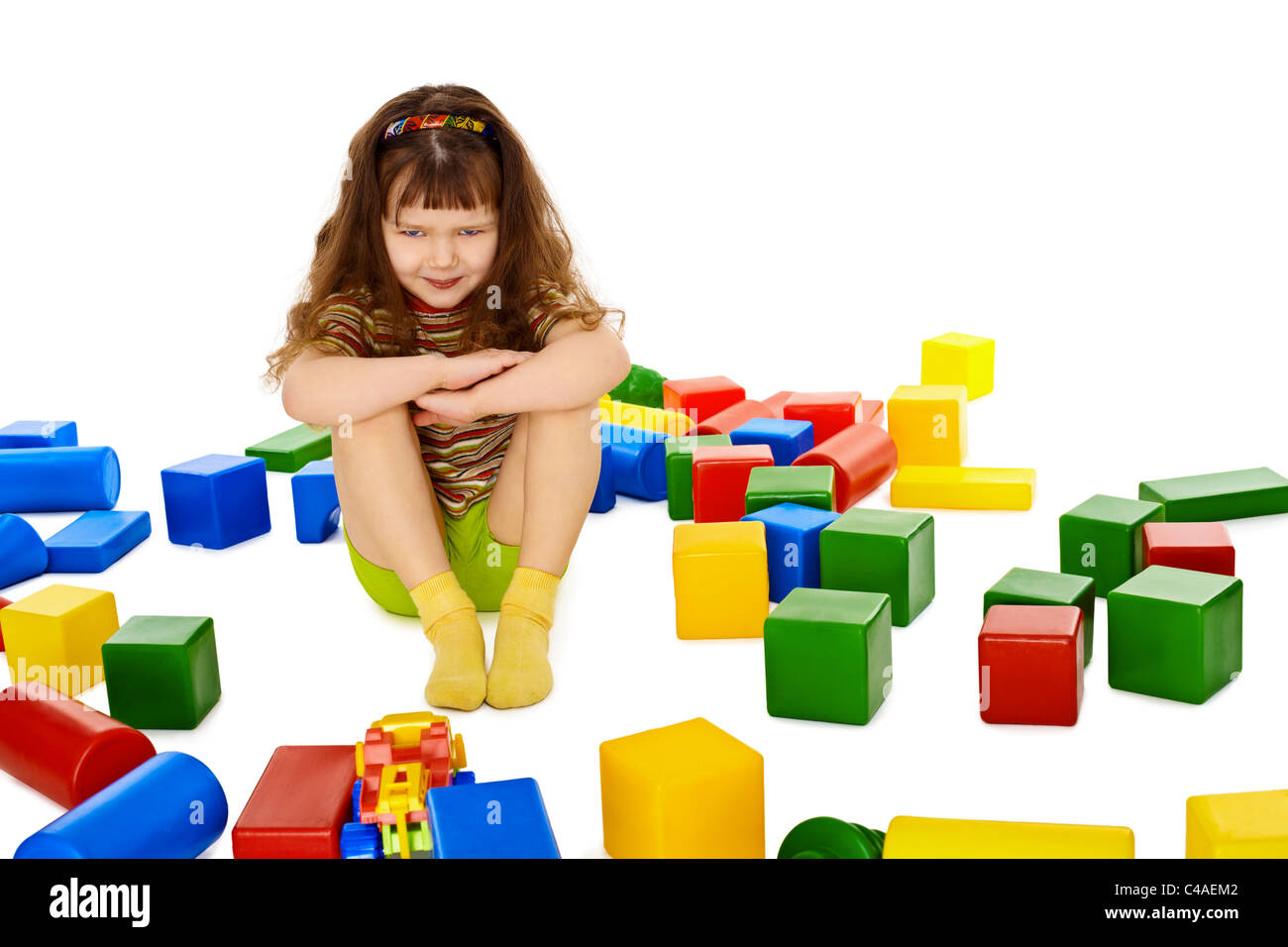 Angry little girl among the scattered toys isolated on white background ...