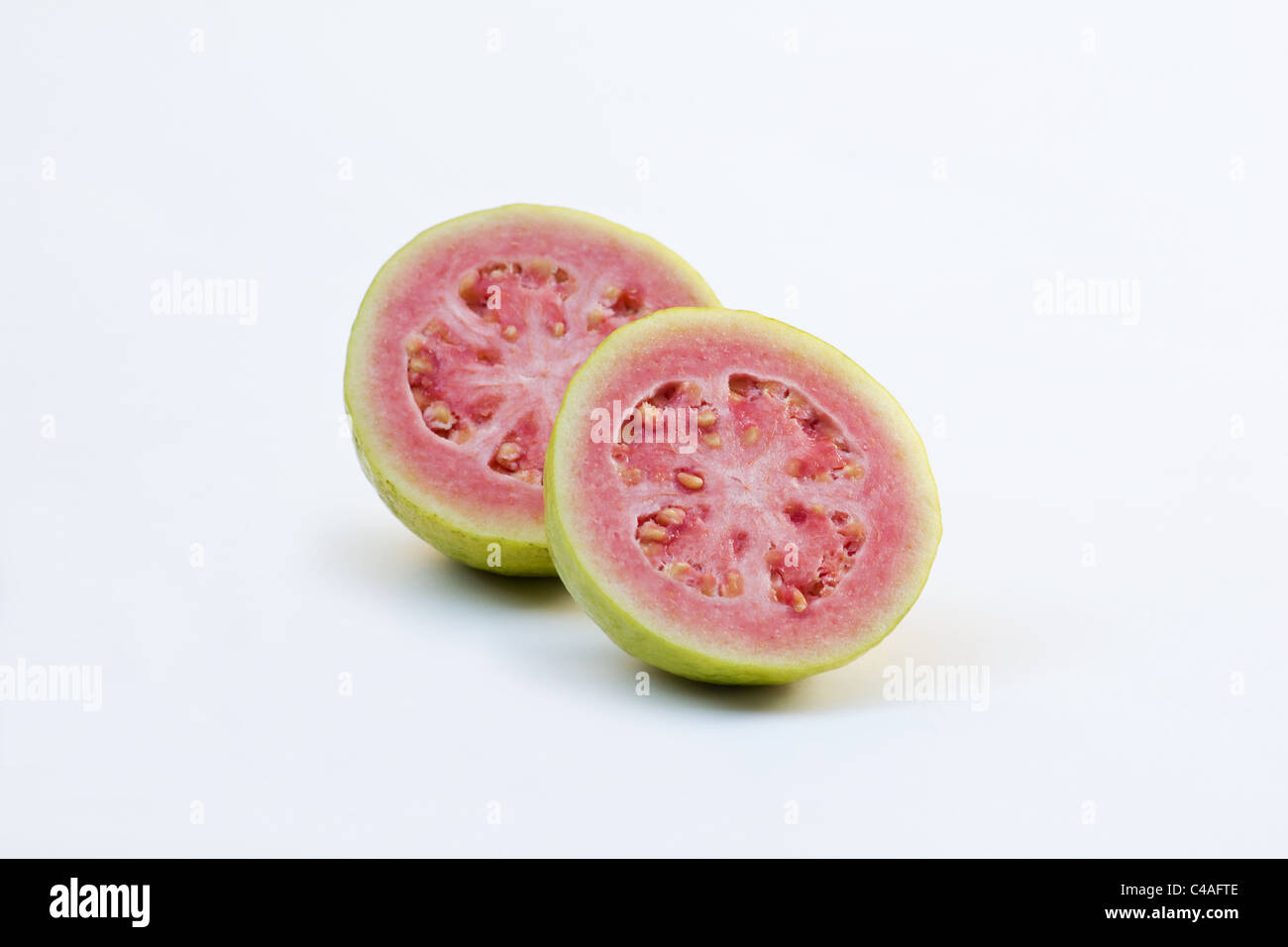 Close-up of guava (Psidium guajava) cut in half on white background ...