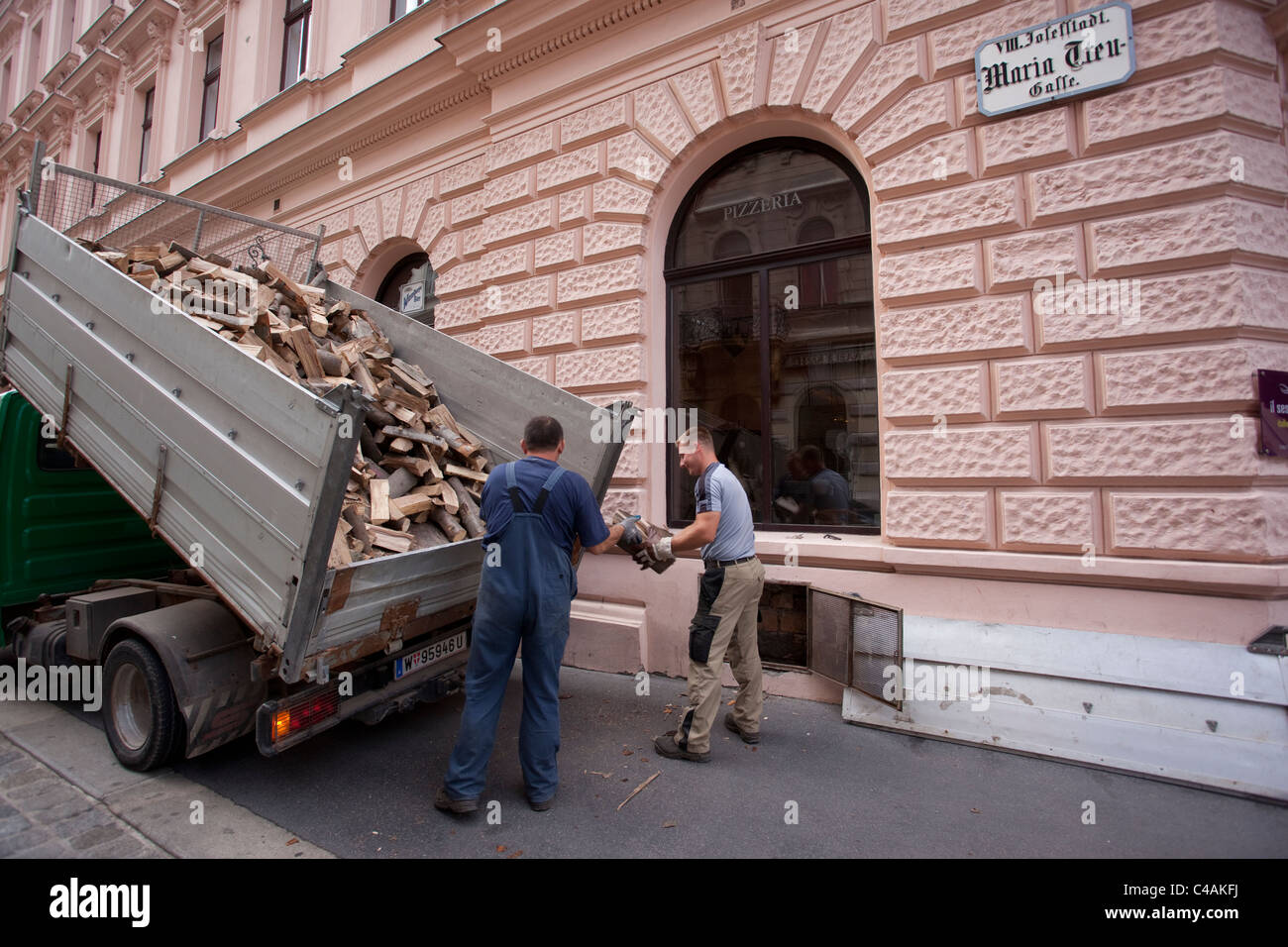 Men loading a restaurant basement with wood burning timber in Vienna ...