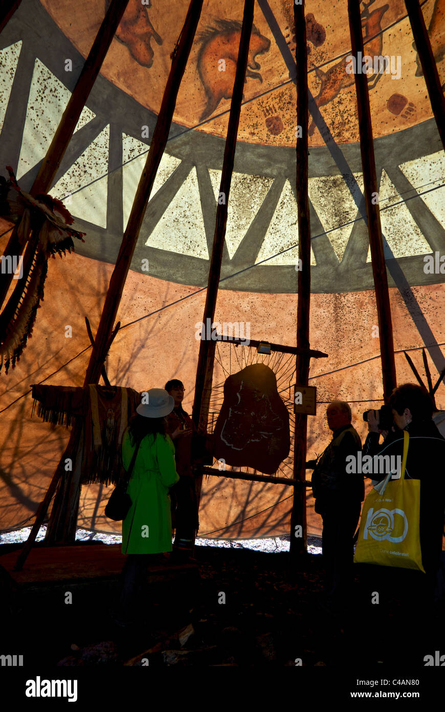 Visitors in silhouette inside traditional tepee display Huron-Wendat ...